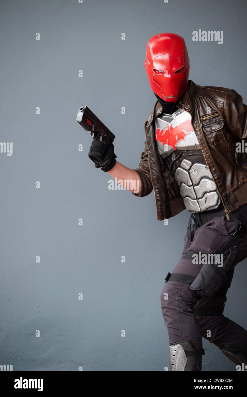 A male cosplayer in a costume with a red helmet, leather jacket, and ...