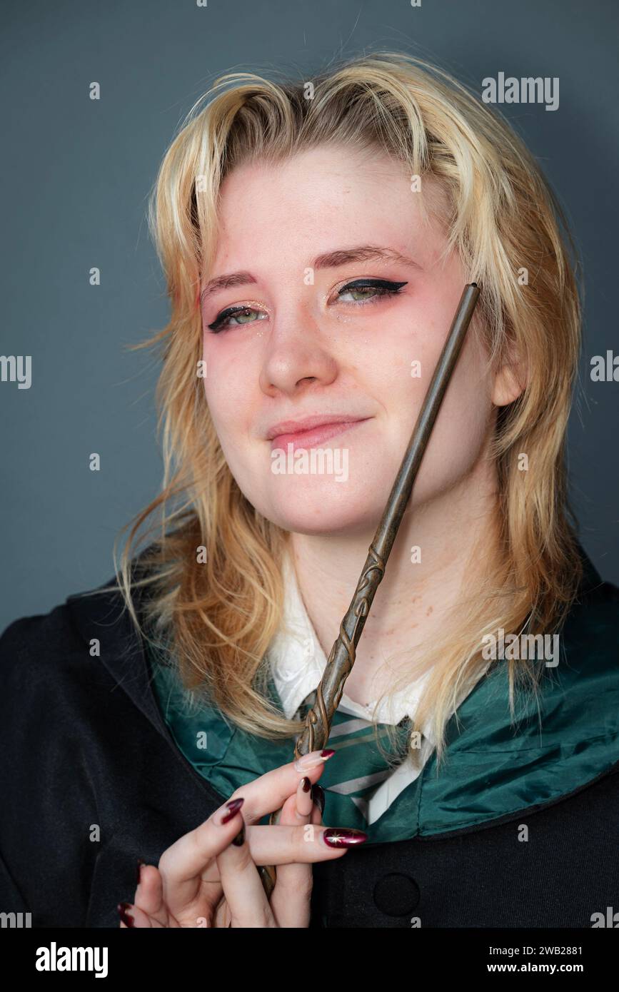 A Caucasian blonde female cosplayer dressed as a wizard with a magic ...