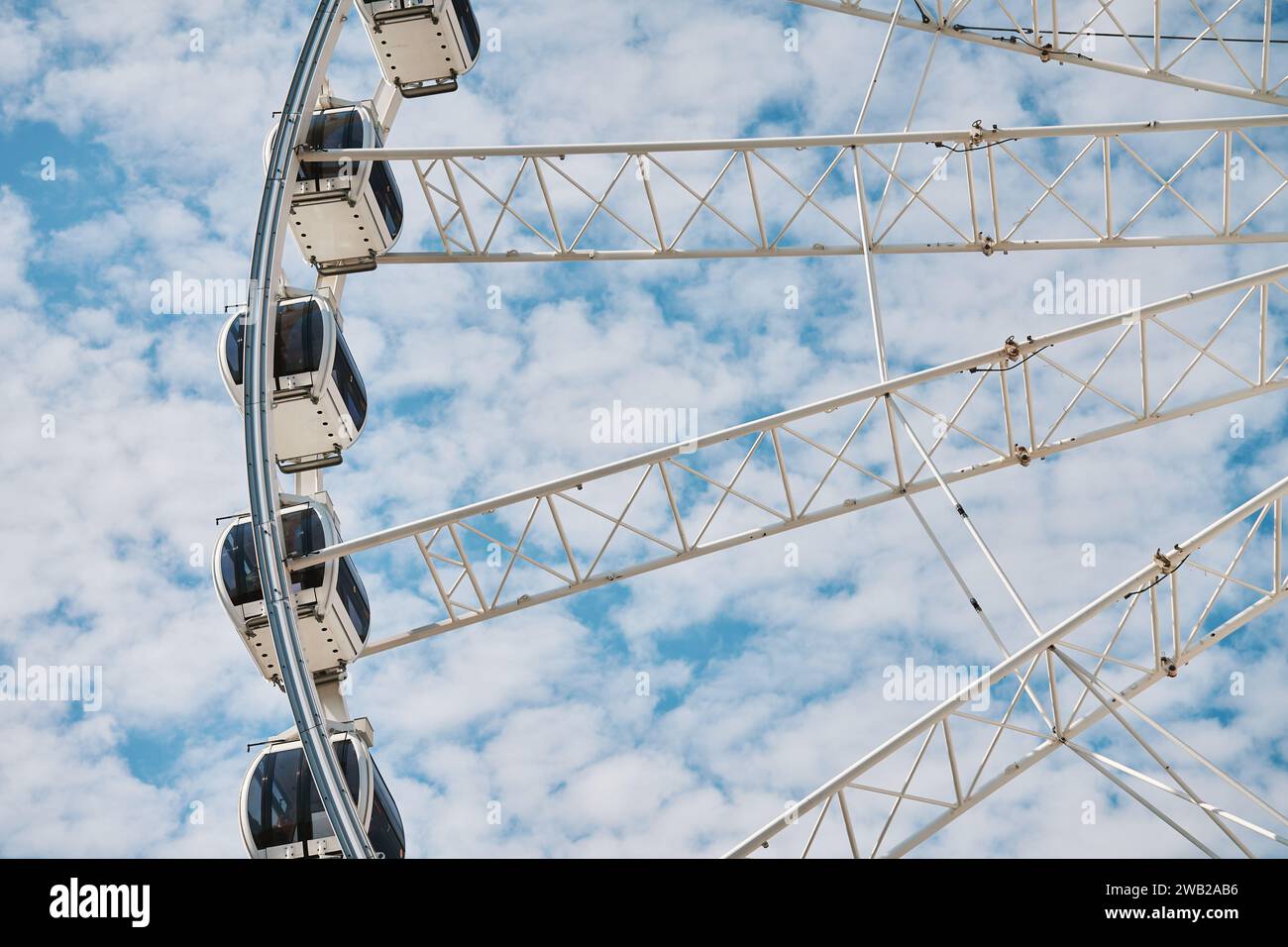 Ferris wheel rotates against background of blue cloudy sky. Amusement ...