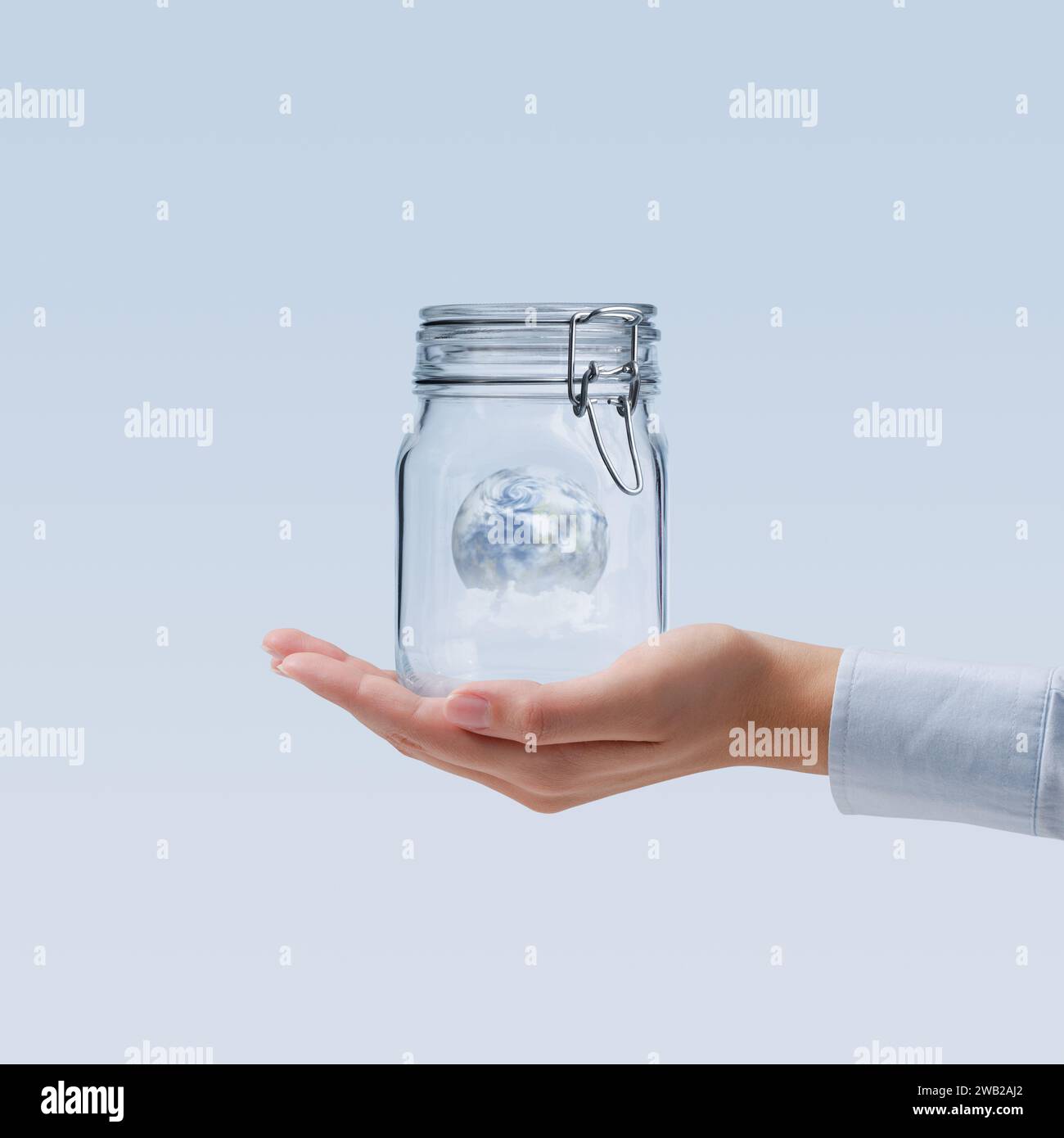 Female hand holding a sealed glass jar containing planet Earth ...