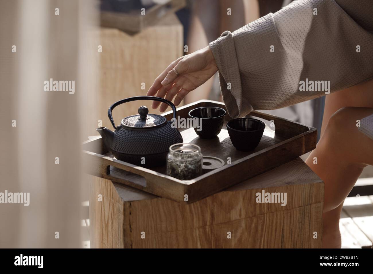 Black cast iron tea pot with herbal tea set up on wood tray ...
