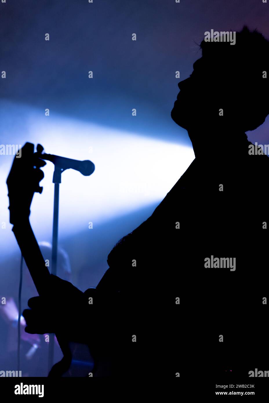 A silhouette of a male singer performing on stage, singing into a ...
