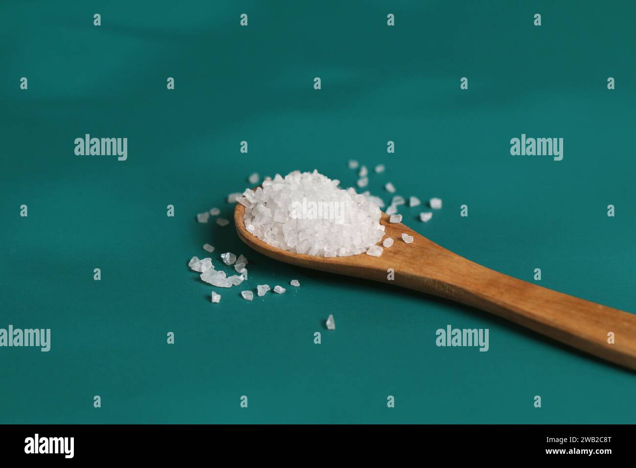 Coarse salt crystals on a blue table. Wooden spoon with sea salt ...