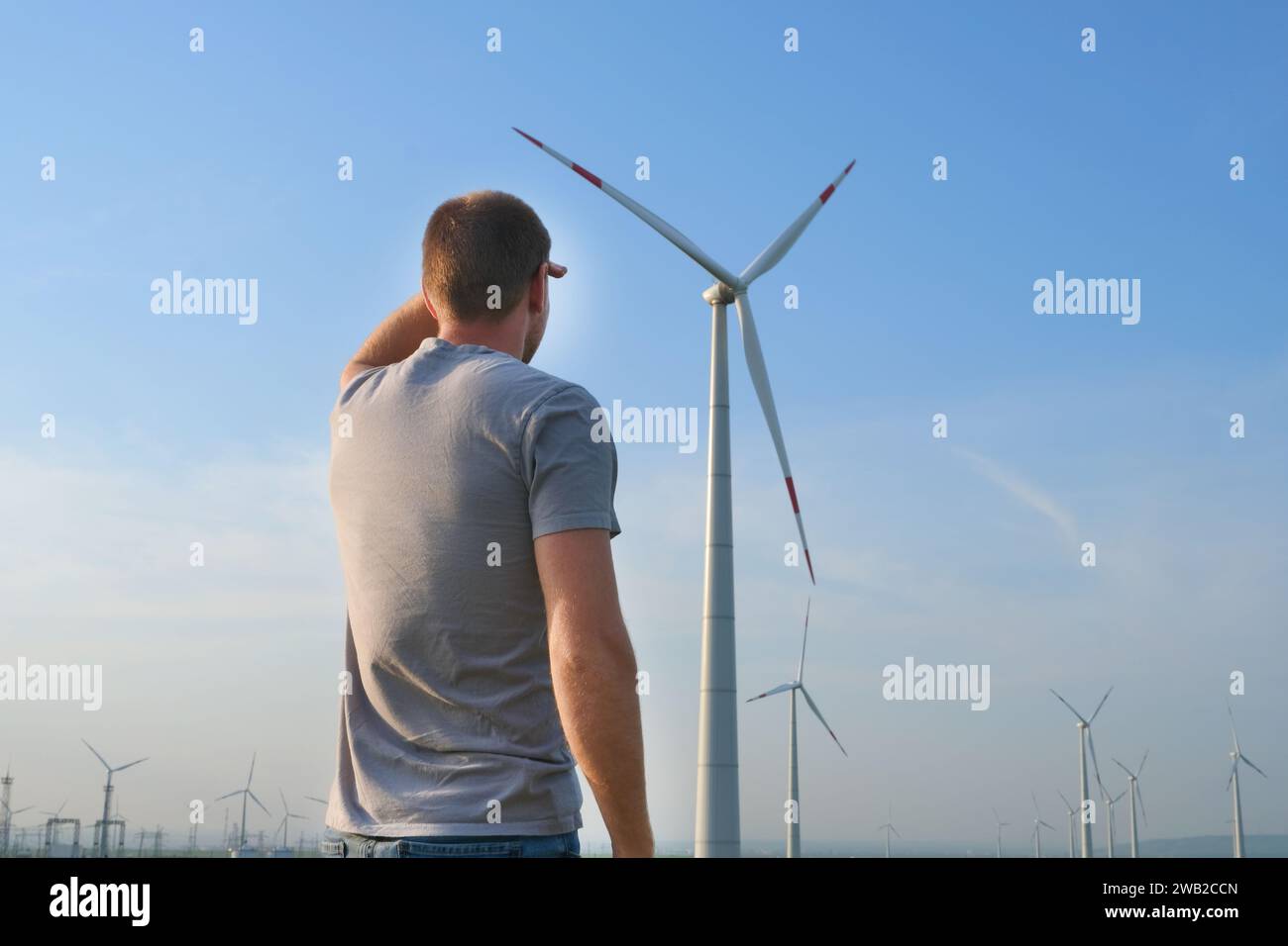 The man stands with his back and looks at the wind turbine. Wind Energy ...