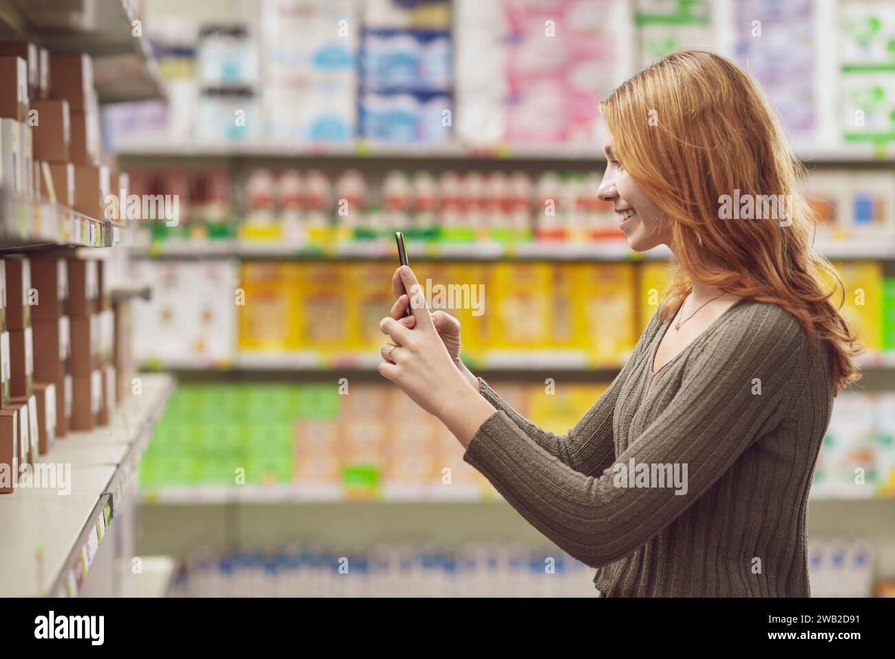 Young woman doing grocery shopping at the supermarket, she is checking ...