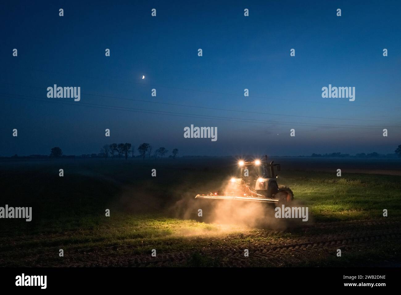 Evening with a tractor in a field with a crescent moon Stock Photo - Alamy