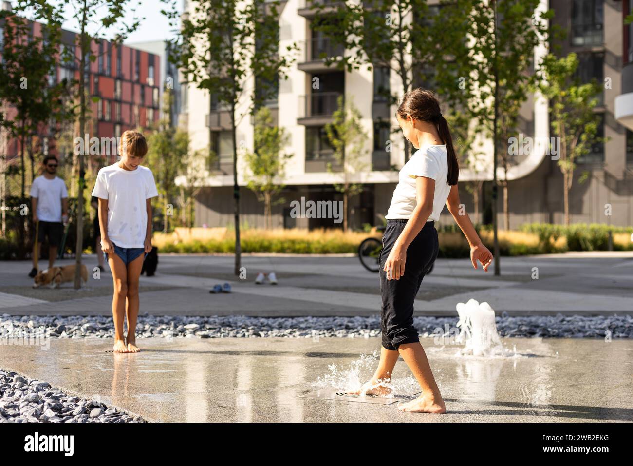 Cheerful young teen girl in city fountain, girl in wet clothes is ...