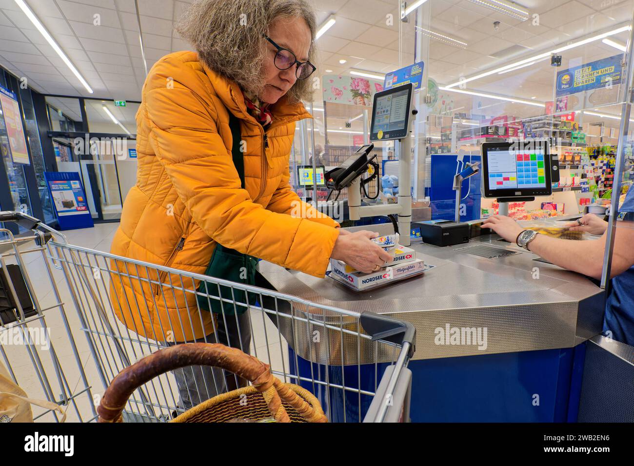Im Supermarkt. Die Kundin mit ihren Einkaufswagen an der Kasse ...