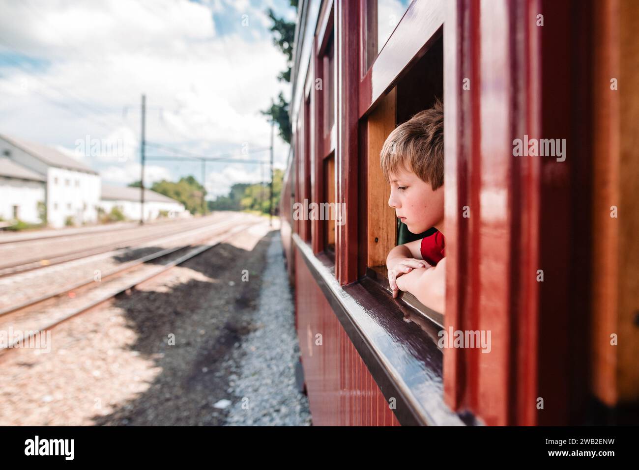 Side angle of boy looking out open train window at empty tracks Stock ...