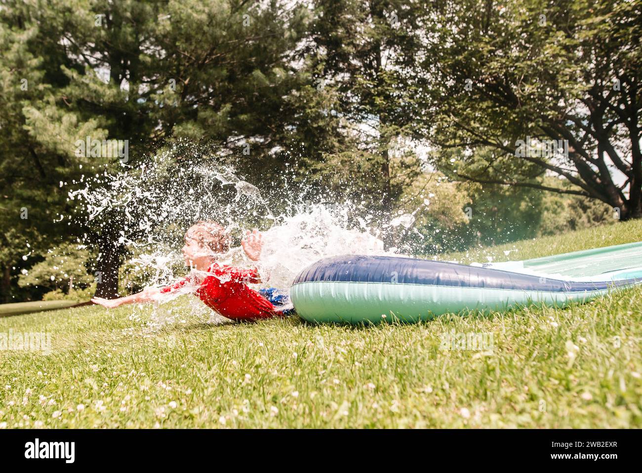Side view of child in a splash of water at end of slip n slide Stock ...