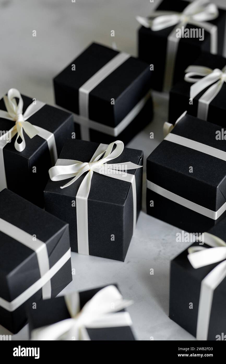 Black gift boxes with white ribbon on a white table Stock Photo - Alamy