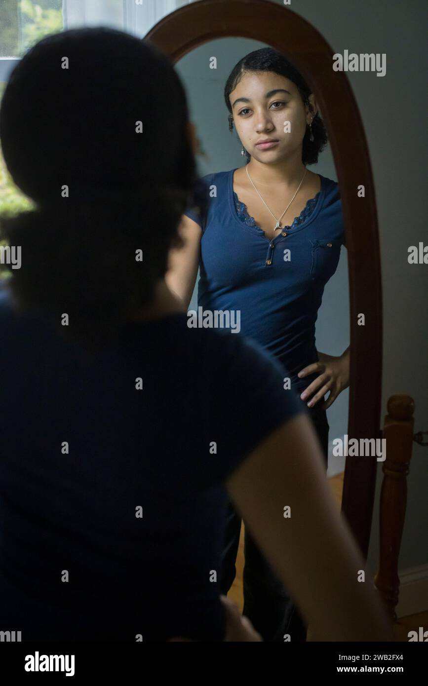 Biracial teen girl looks at herself critically in the mirror Stock ...