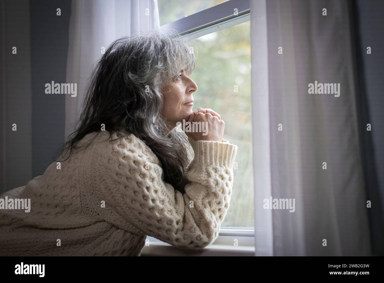 Older white woman looking out window with serious expression Stock ...