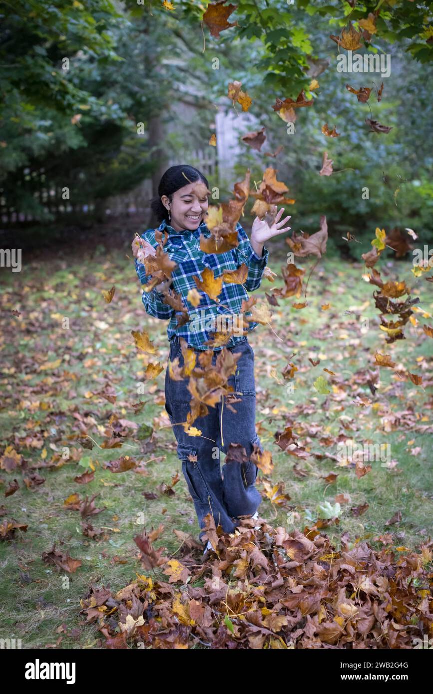 Biracial teen girl throwing up fall leaves and laughing Stock Photo - Alamy