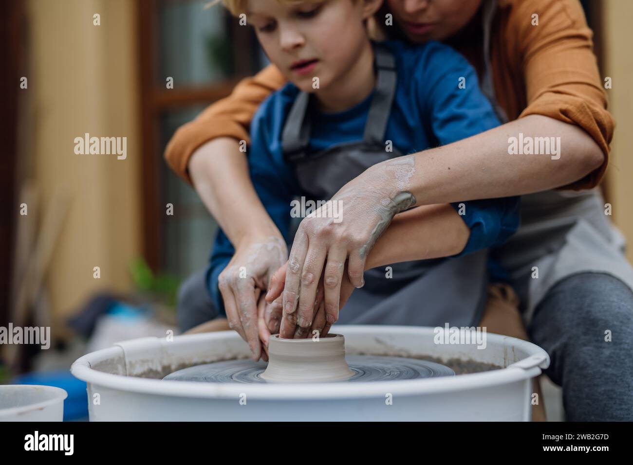Mother teaching son how make pottery on pottery wheel. Child creative ...