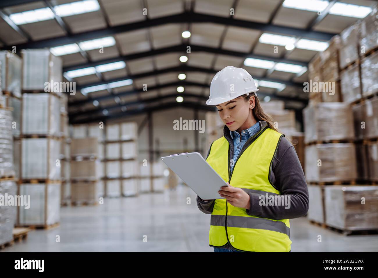 Female warehouse worker reading product order, order picking. Warehouse ...