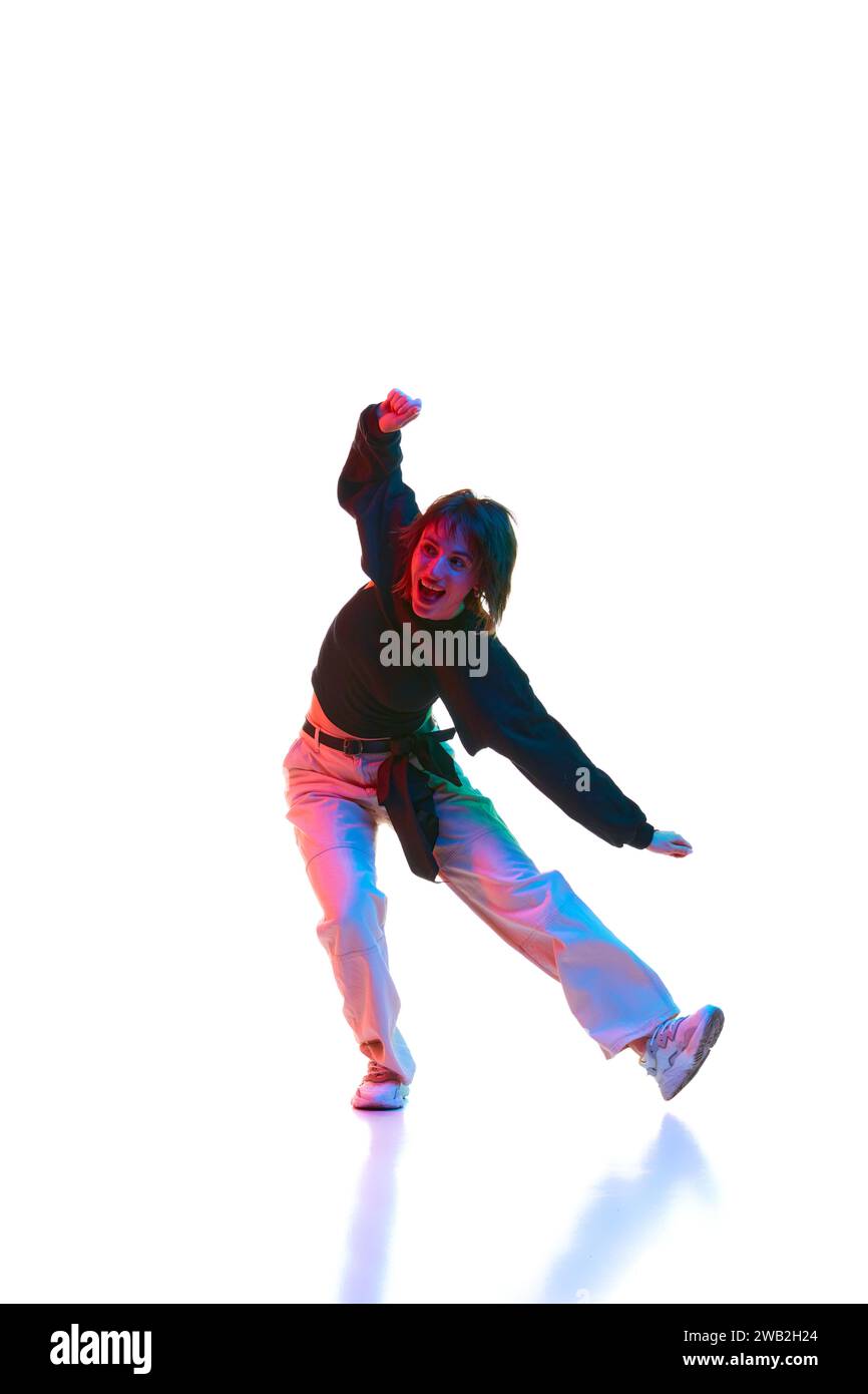 Cheerful, positive young woman in casual clothes dancing hip hop ...