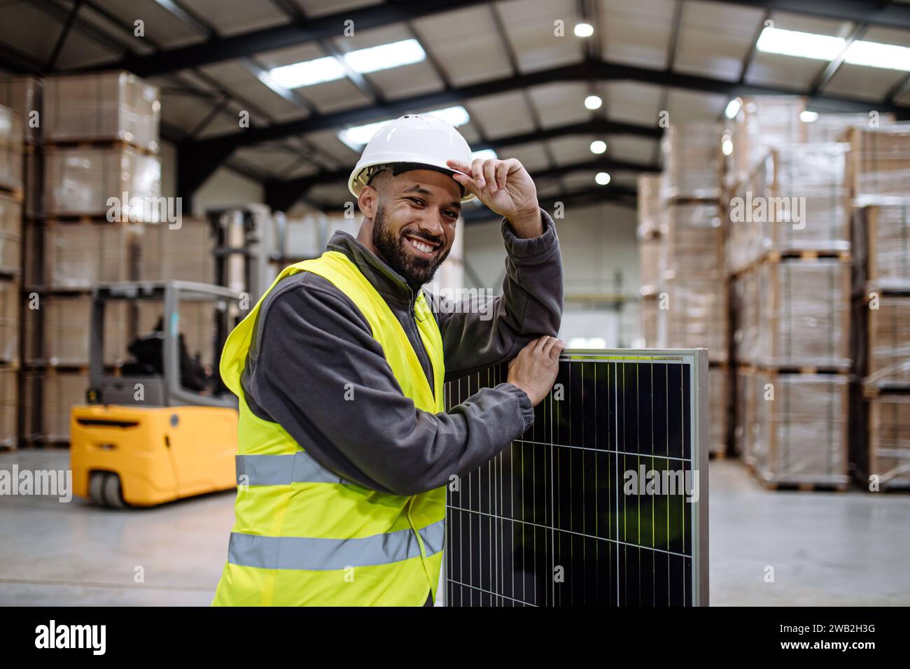 Handsome worker holding solar panel in warehouse, factory. Solar panel ...