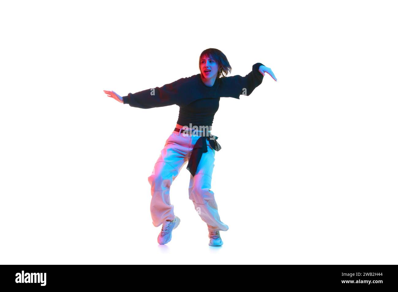 Cheerful, positive young woman in casual clothes dancing hip hop ...