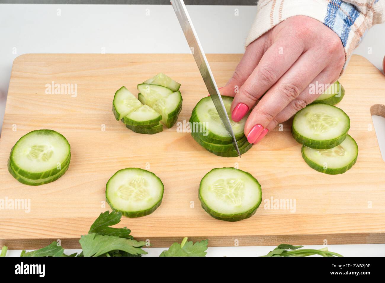 Cutting cucumbers into small pieces for preparing salad on a kitchen ...
