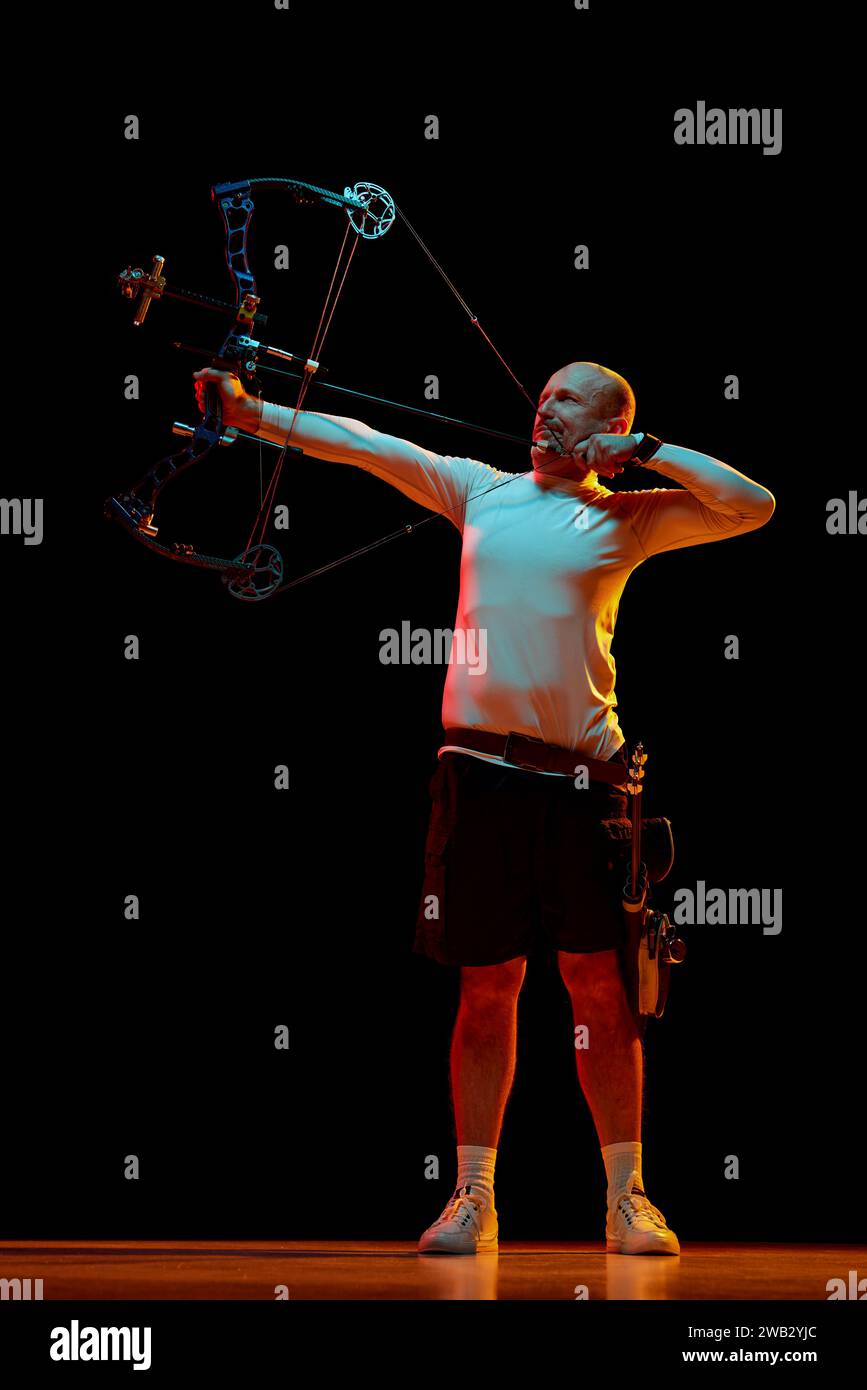 Full-length of man, archer in motion, training, aiming archery bow on ...