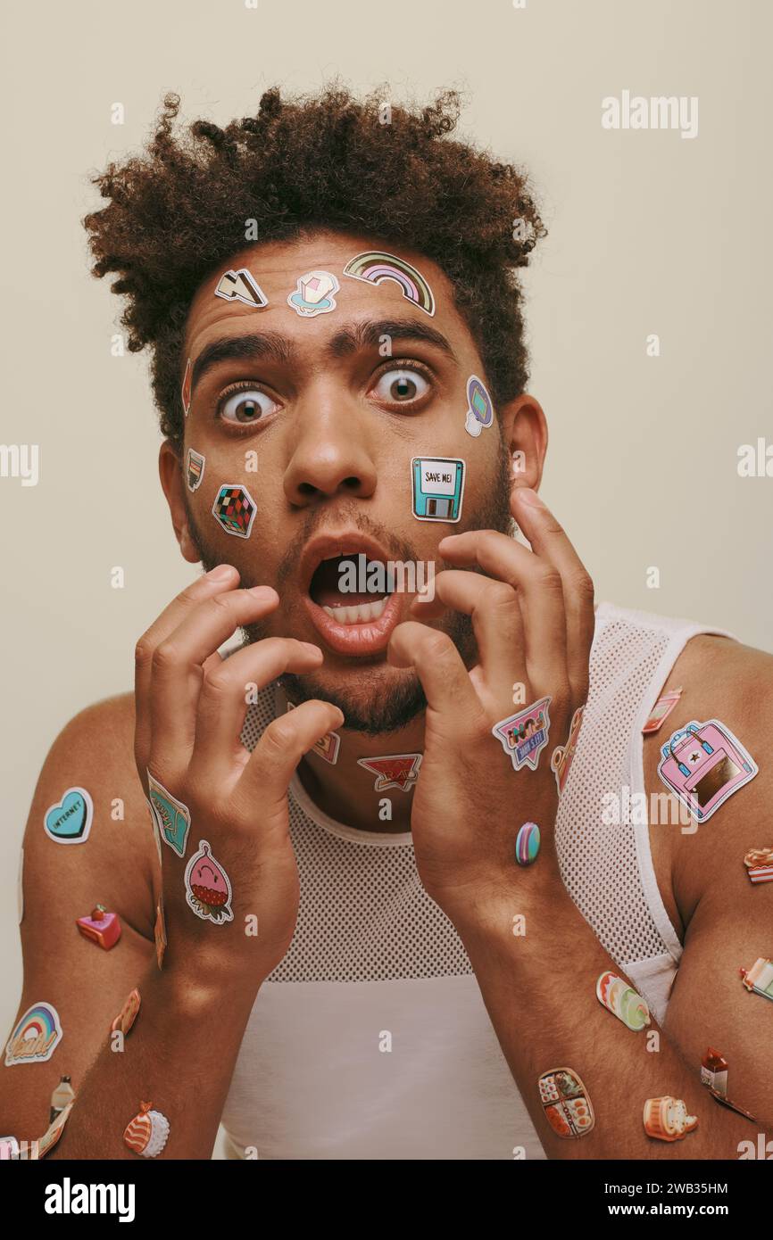 shocked african american guy in tank top with stickers on face looking ...