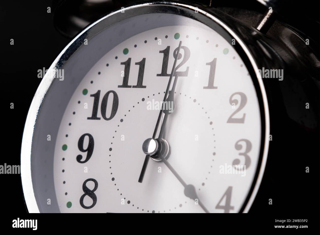 Close-up of a retro alarm clock face on a black background. Clock hands ...