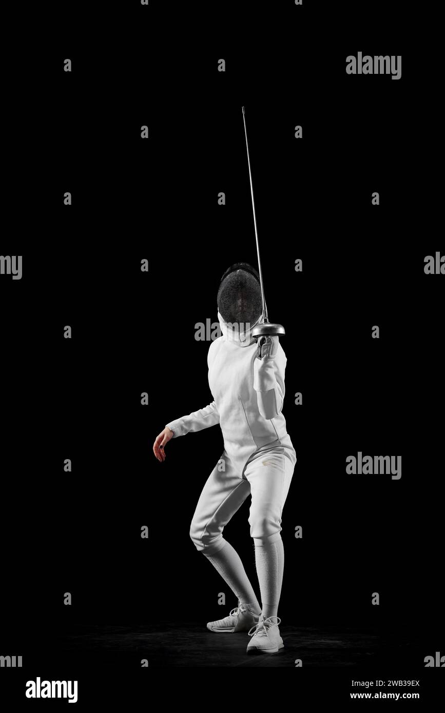 Swordswoman, professional female fencer's poised stance, against black ...