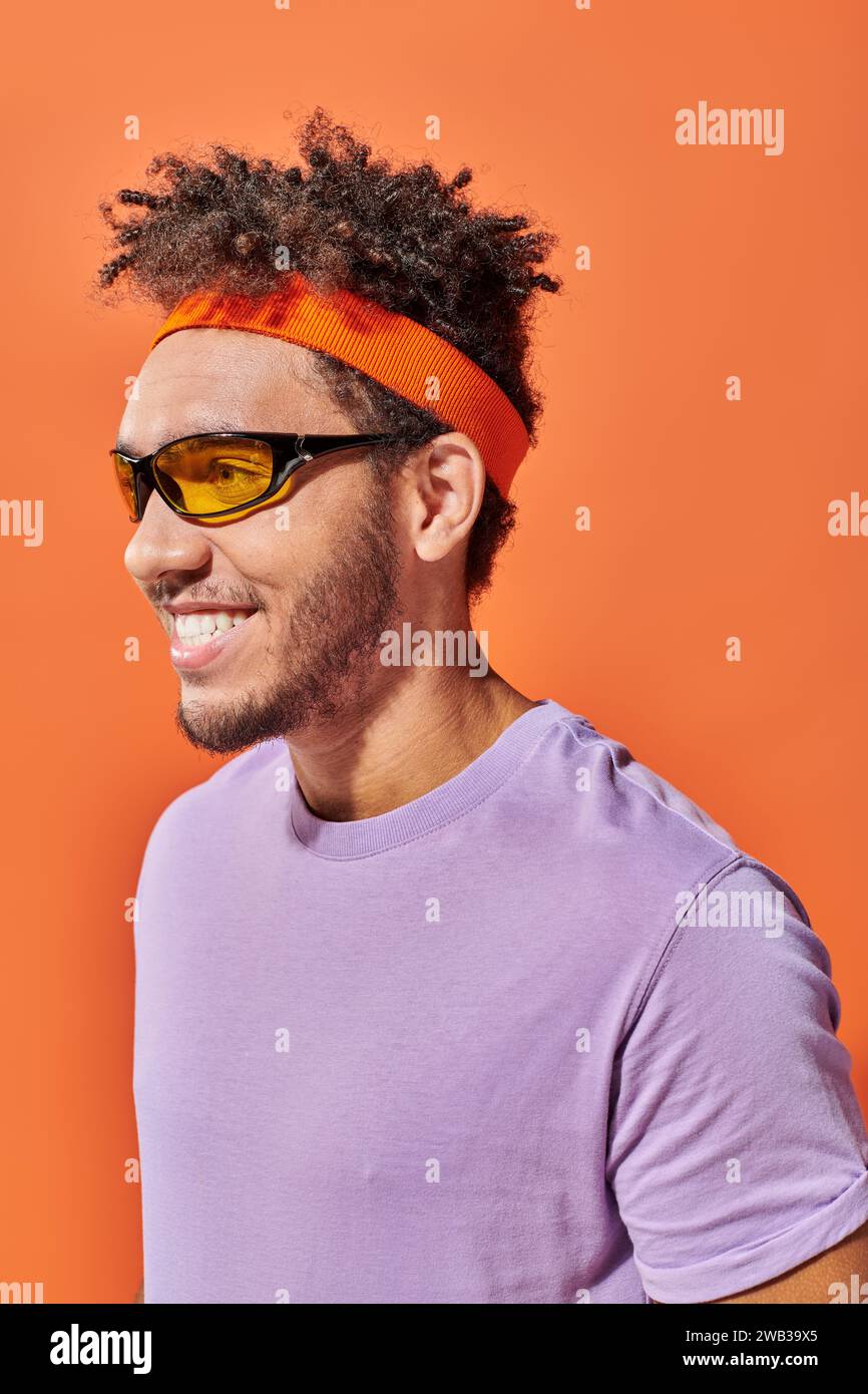 happy african american fella in eyeglasses looking away on orange ...
