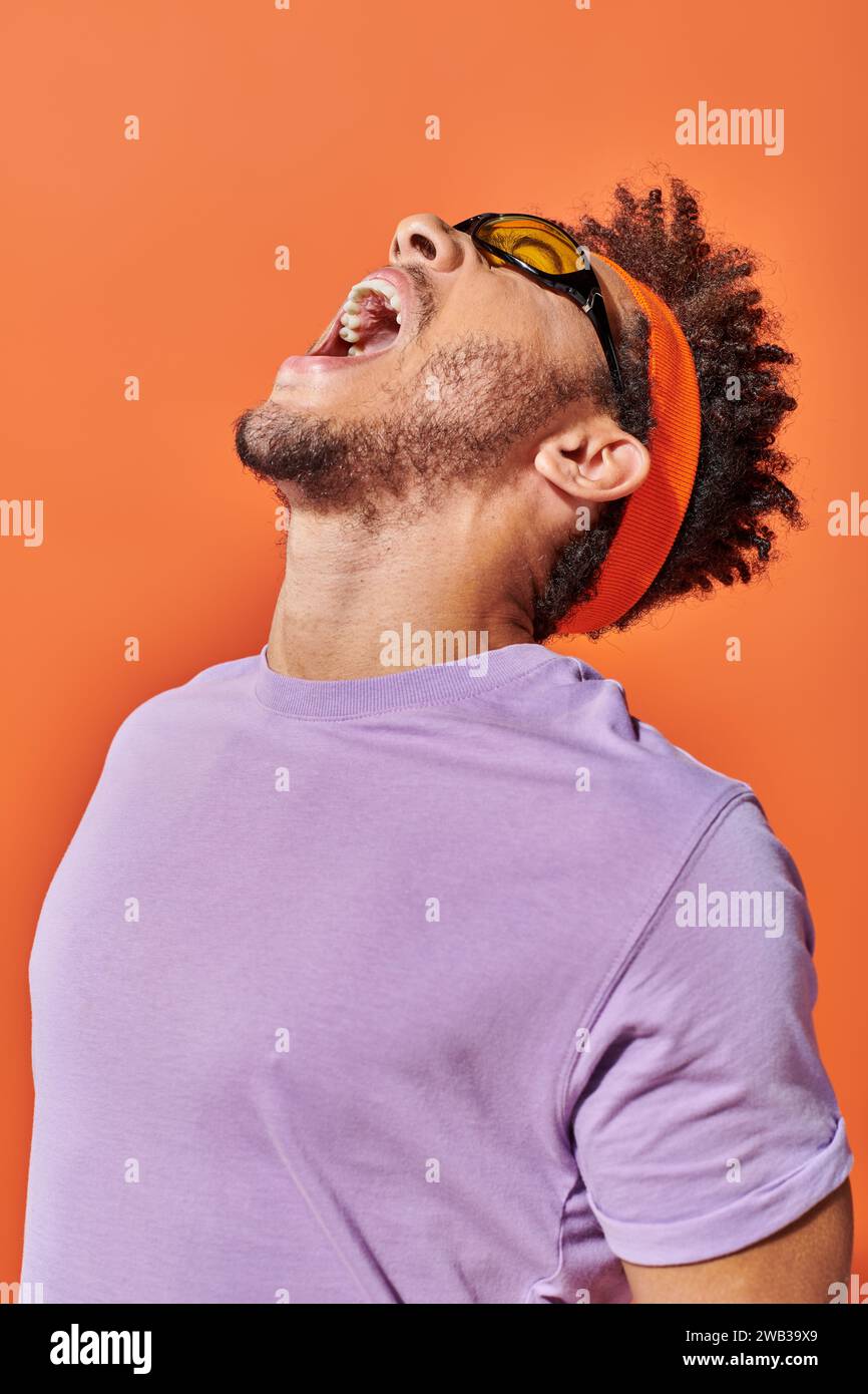 happy african american fella in eyeglasses laughing out loud on orange ...