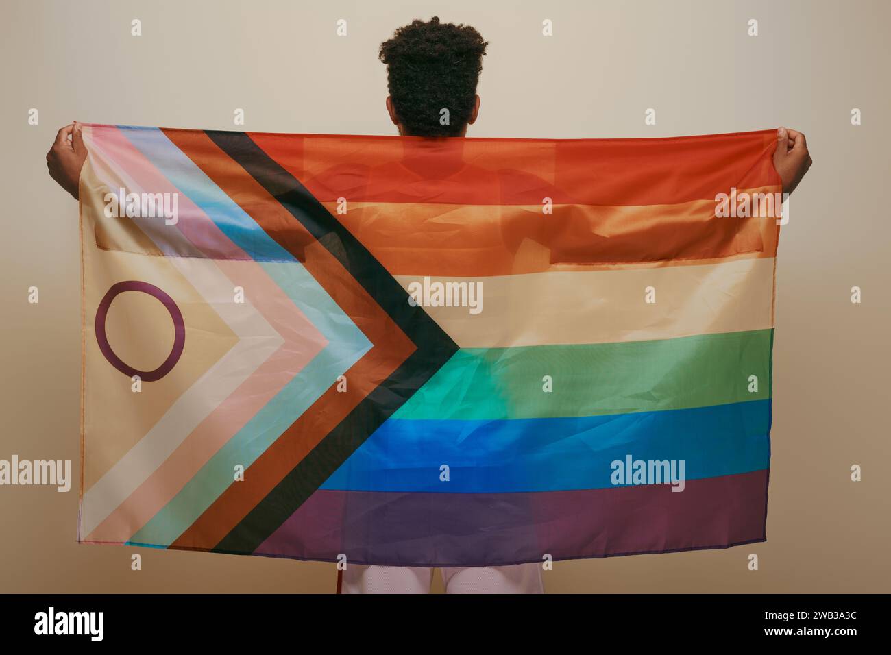 back view of african american man holding rainbow lgbt flag on yellow ...