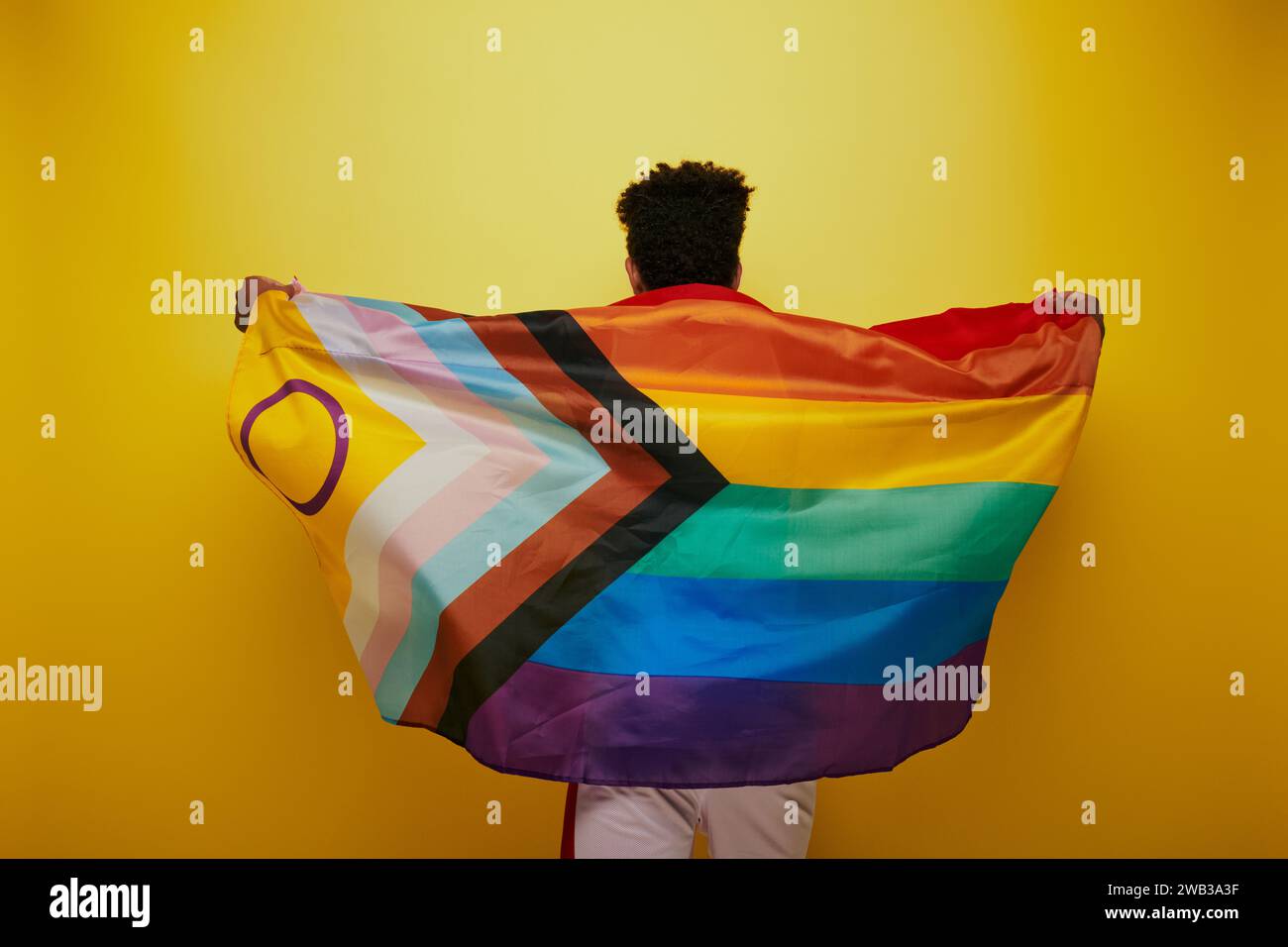 Back View Of African American Man Holding Rainbow Lgbtq Flag On Yellow