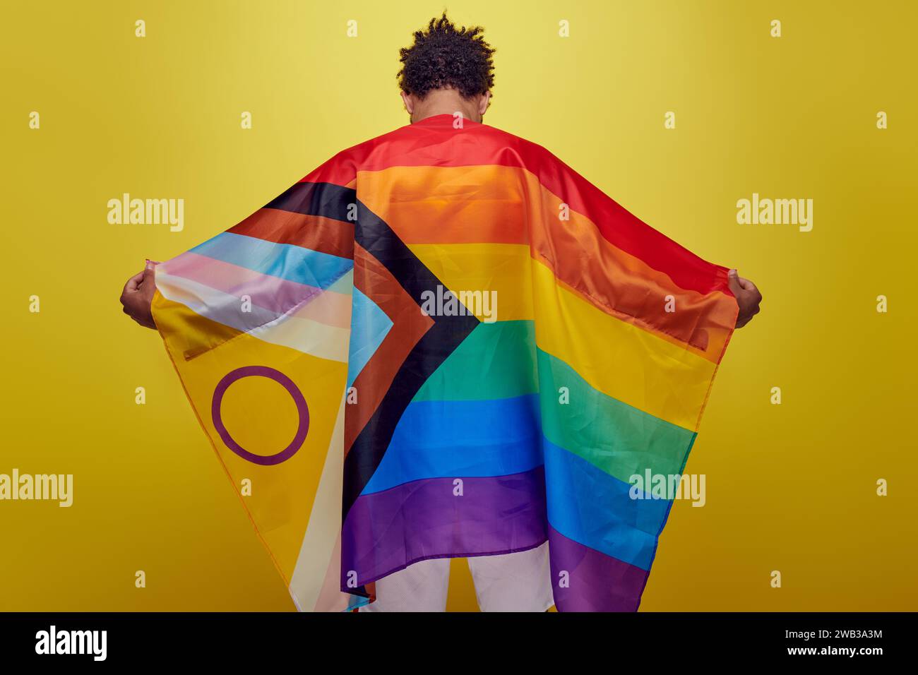 back view of african american guy holding rainbow lgbt flag on yellow ...