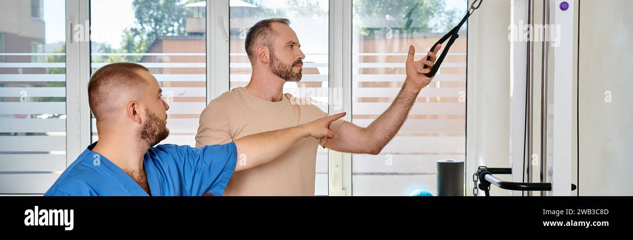 skilled doctor in blue uniform instructing man in gym of kinesio center ...