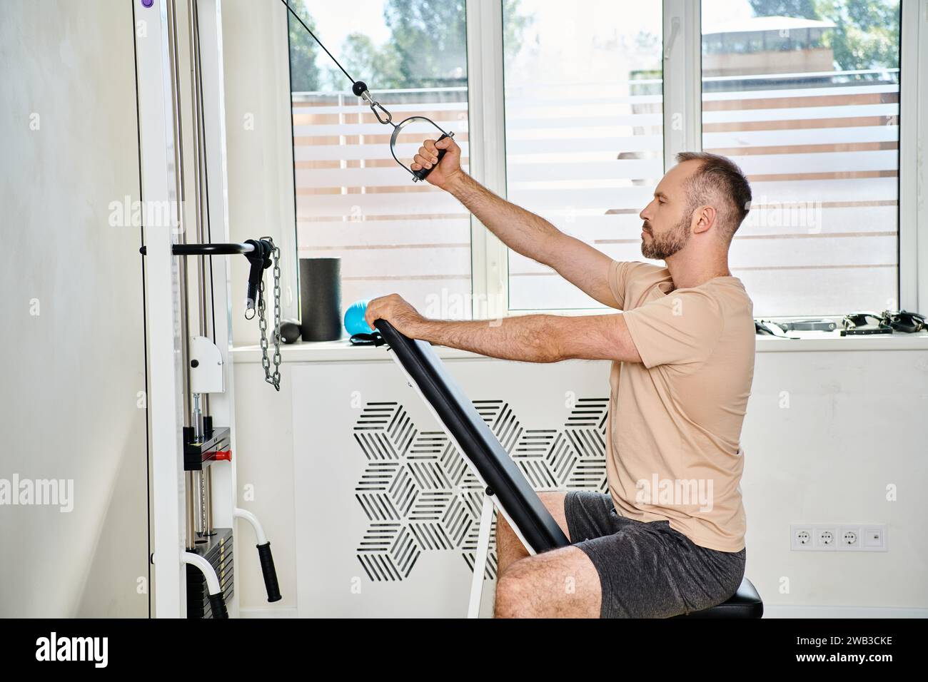 side view of handsome man in sportswear working out on training machine ...