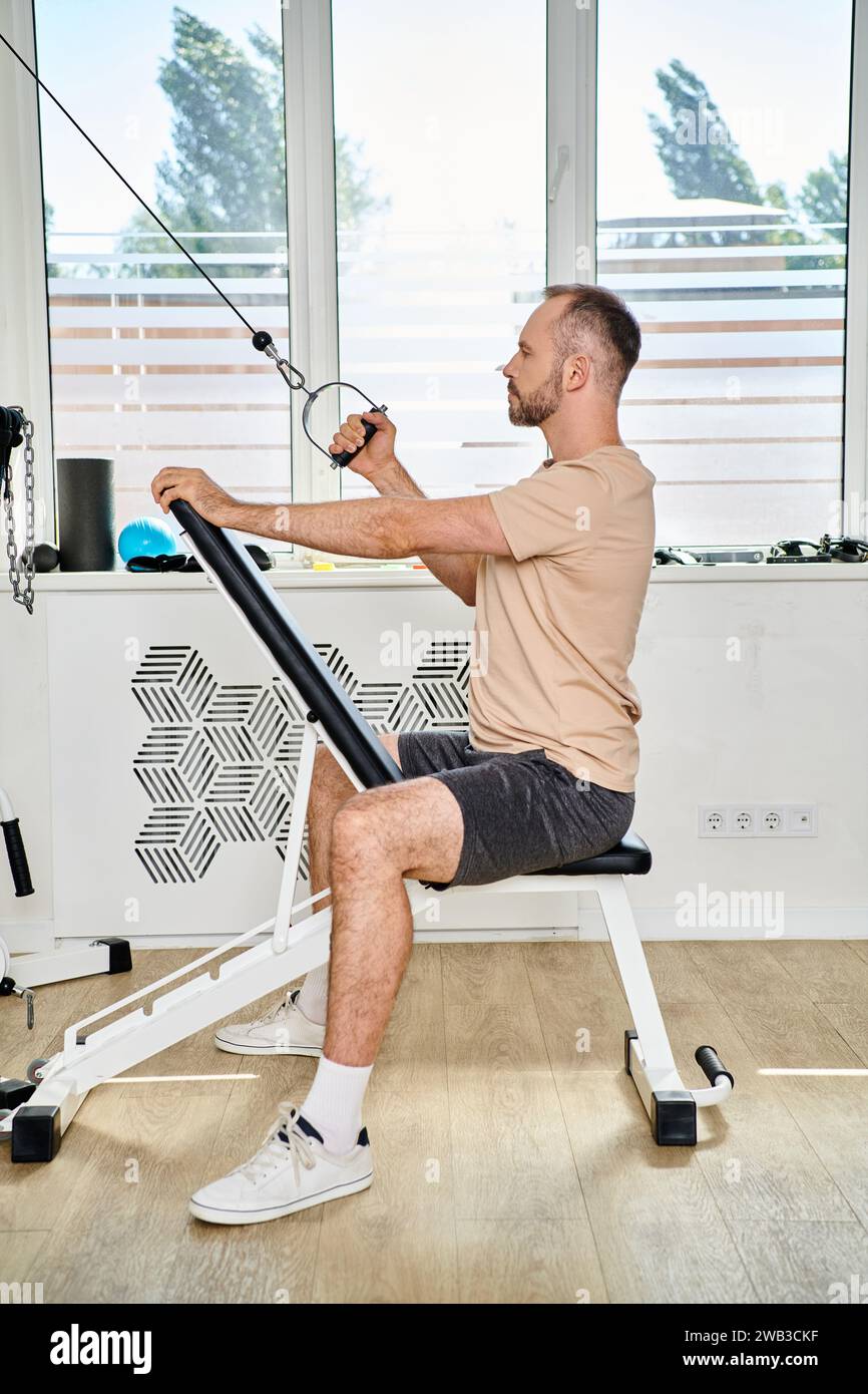 side view of handsome bearded man in sportswear working out on training ...