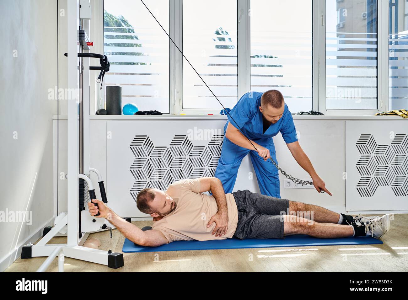 young doctor in blue uniform assisting man training on exercise machine ...