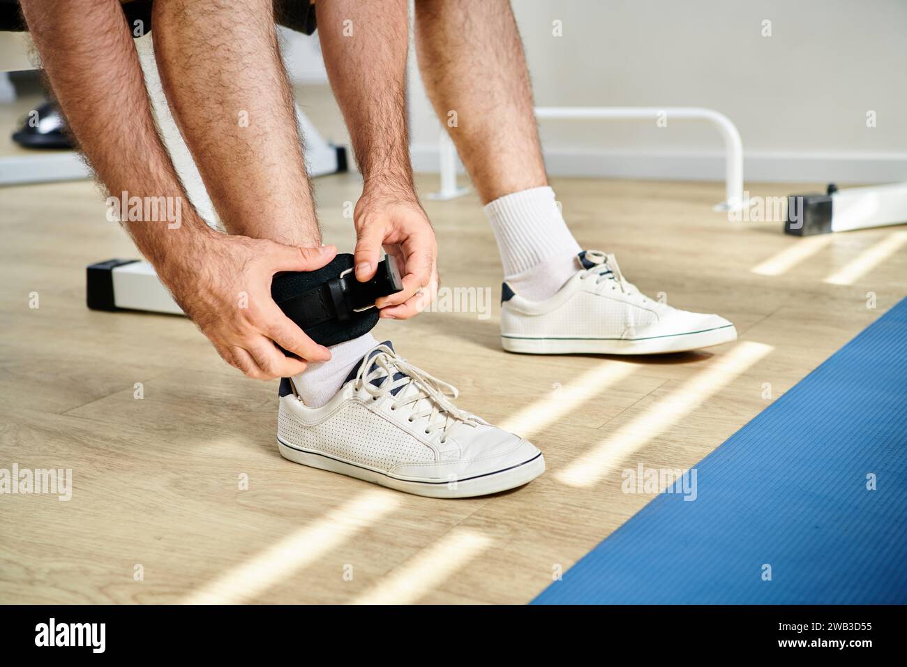 cropped view of man putting fitness leg belt before recovery training ...