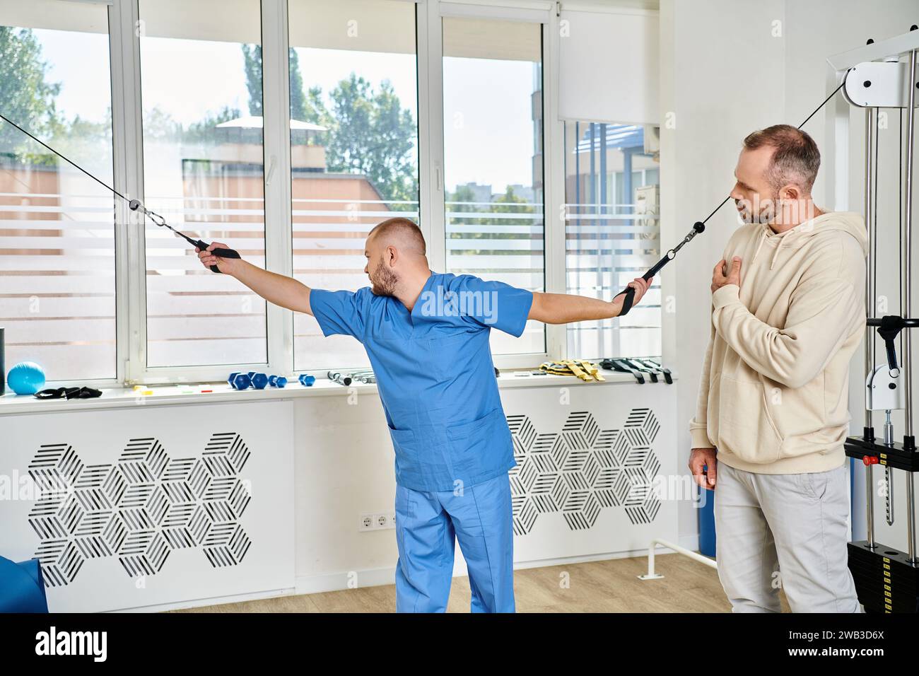 rehabilitologist in blue uniform showing exercise on training machine ...