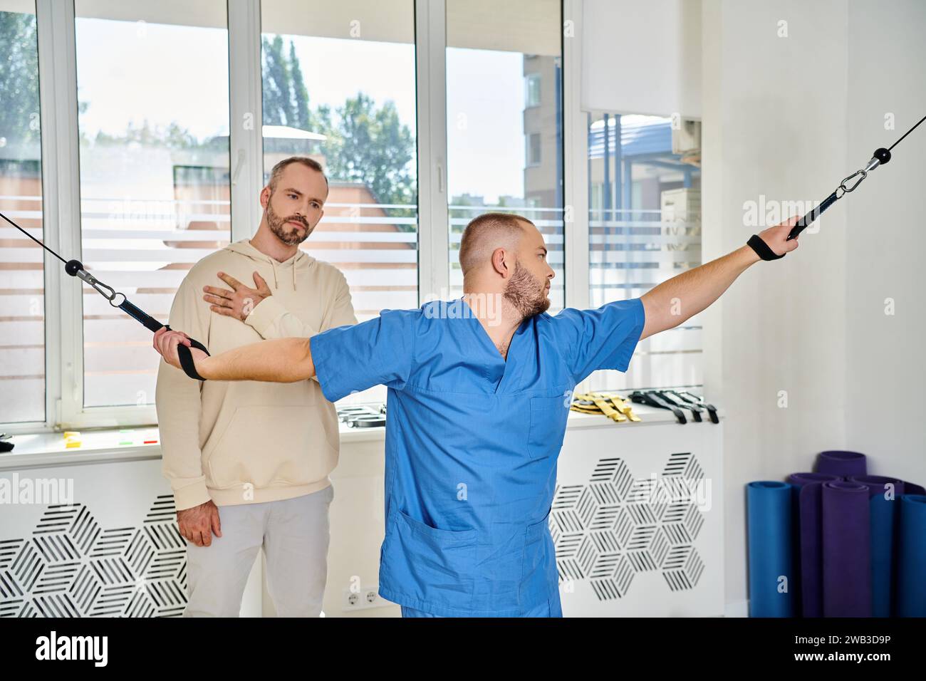 physician working out on exercise machine instructing man with injured ...