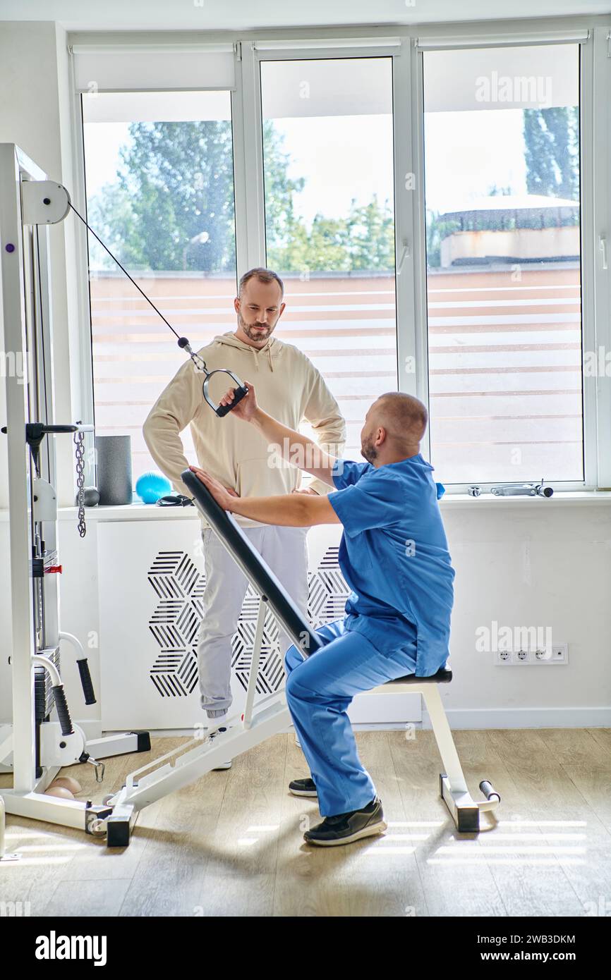 doctor in blue uniform training on exercise machine, instruction of man ...