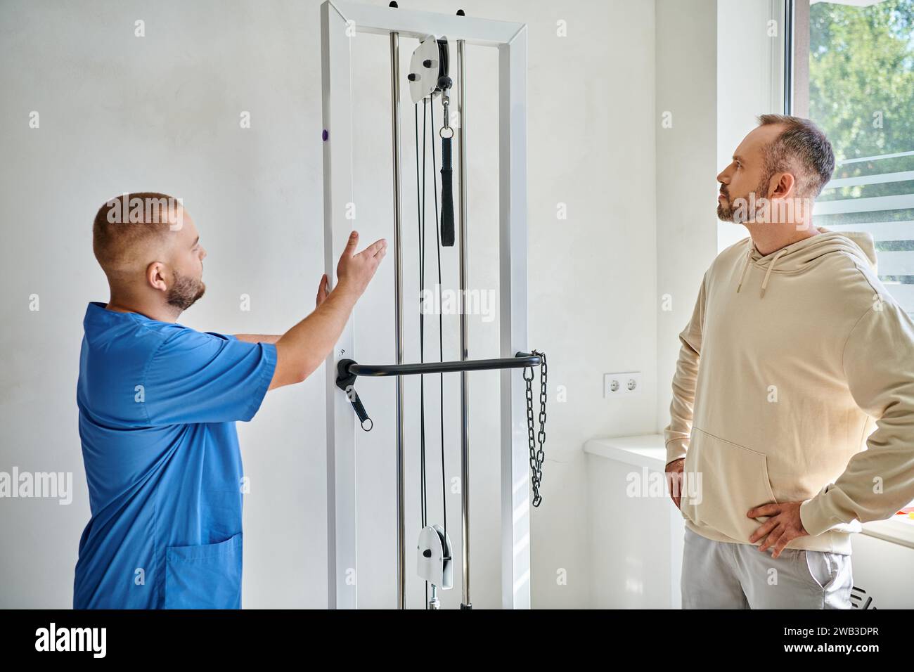 young doctor in blue uniform showing exercise equipment to his patient ...
