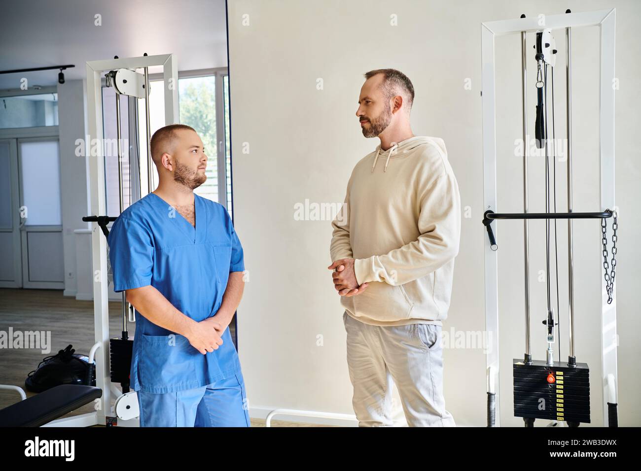 bearded man and professional rehabilitologist in blue uniform talking ...
