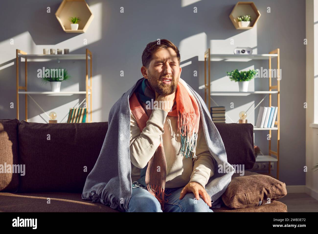Sick man wrapped in blanket feeling sore throat Stock Photo - Alamy