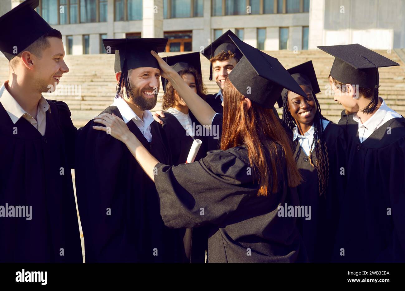 Group of happy university students wearing caps and gowns having fun on ...