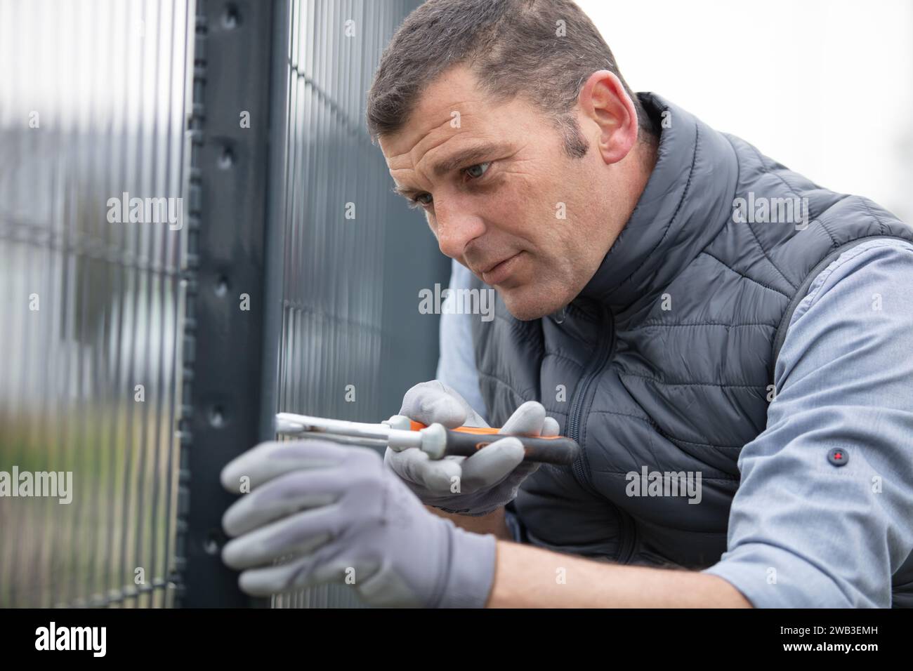 worker using pliers while installing welded metal mesh fence Stock ...