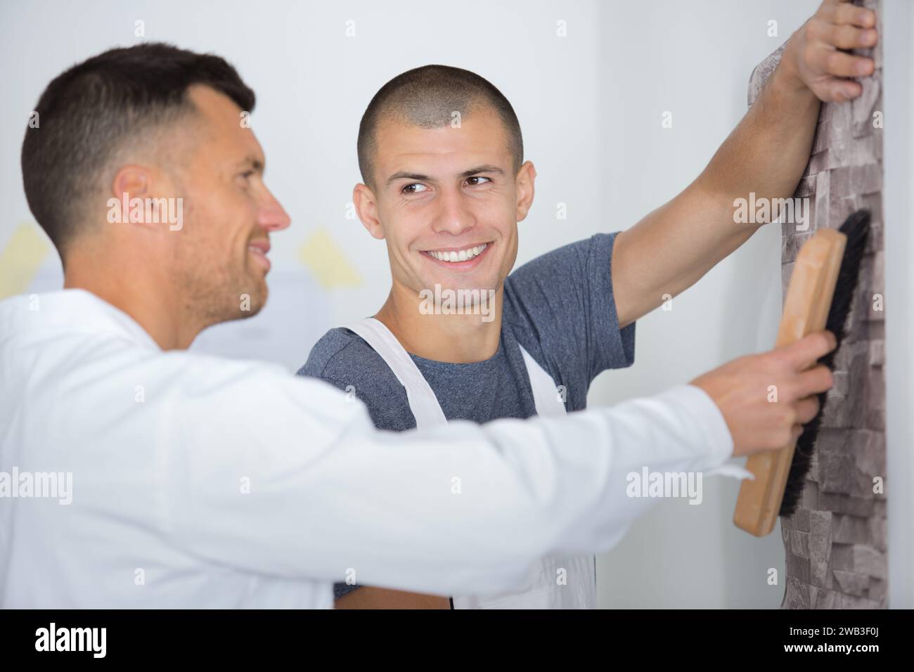 two male decorators putting up wallpaper Stock Photo - Alamy