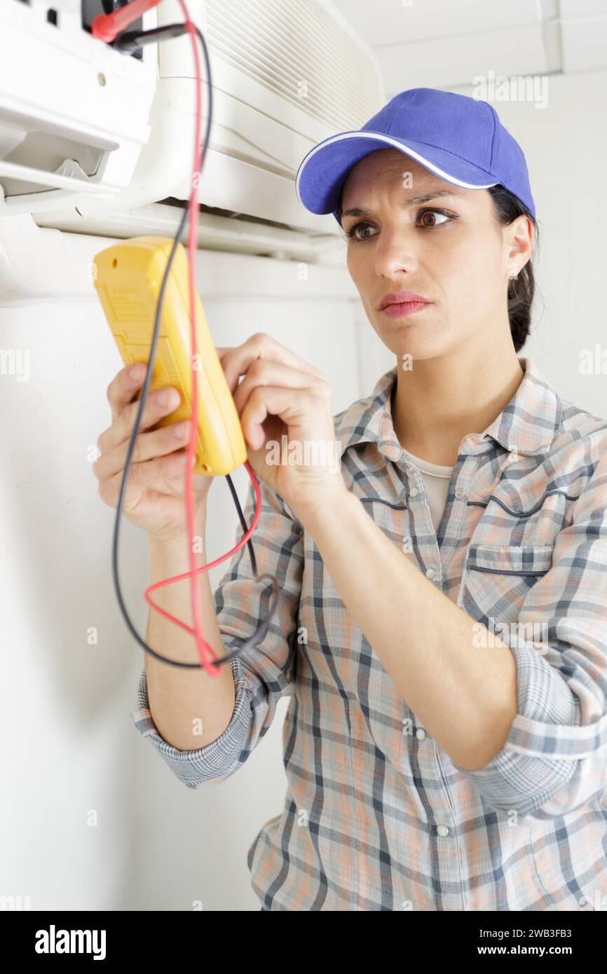 female maintenance engineer testing voltage with digital multimeter ...