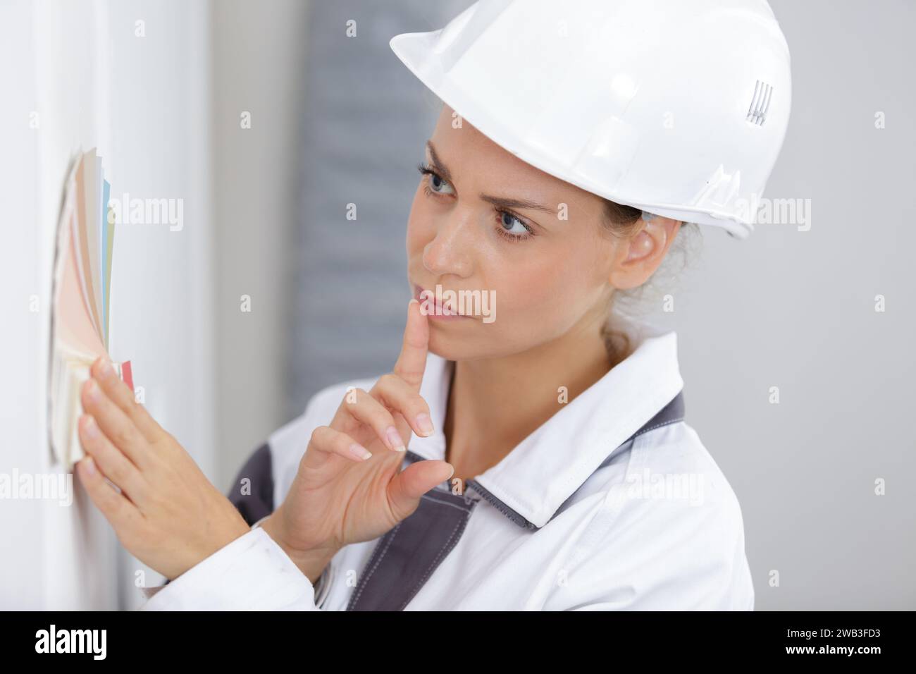 contemplative professional looking at colour charts against the wall ...