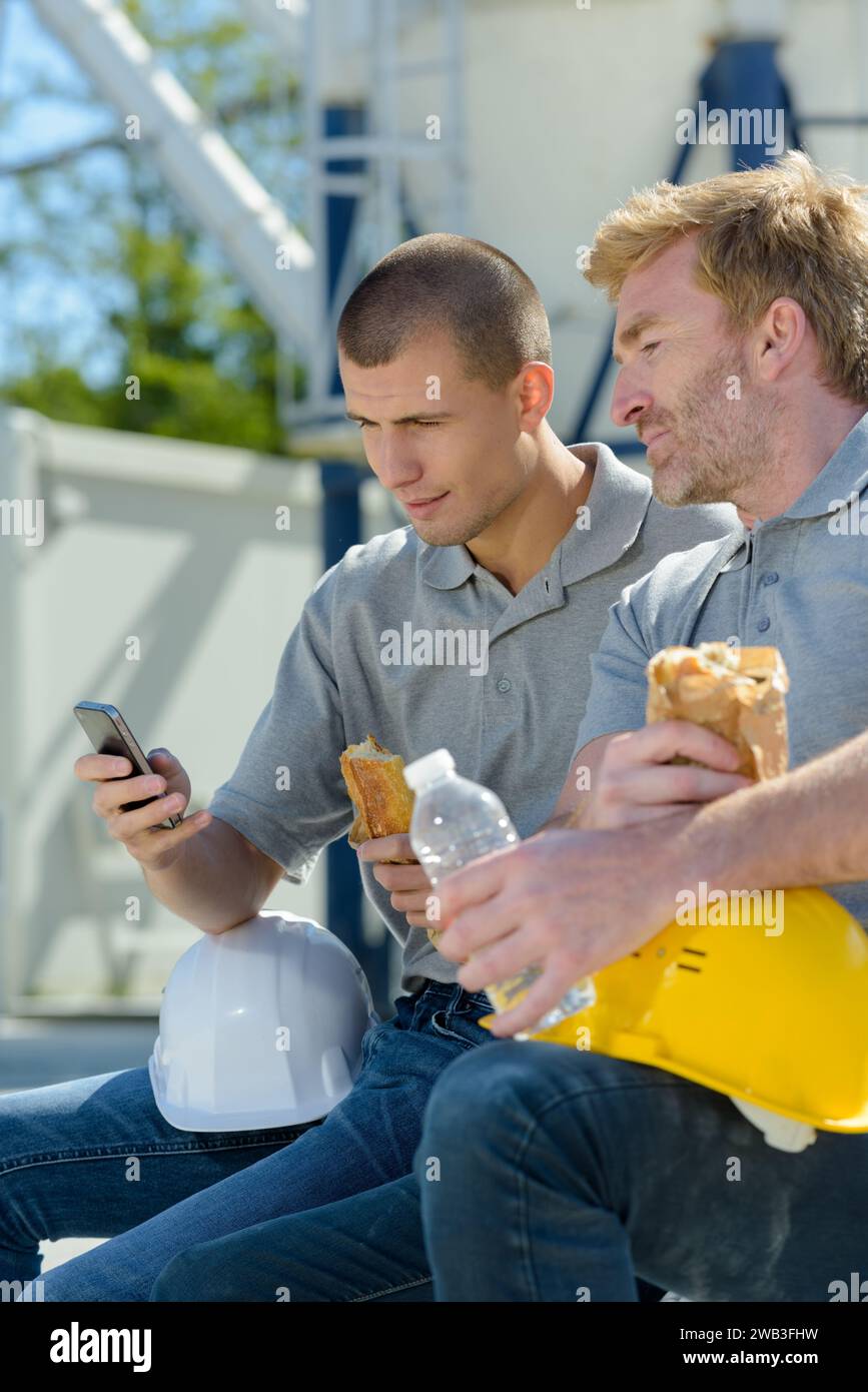 two workers taking break while having their lunch Stock Photo - Alamy